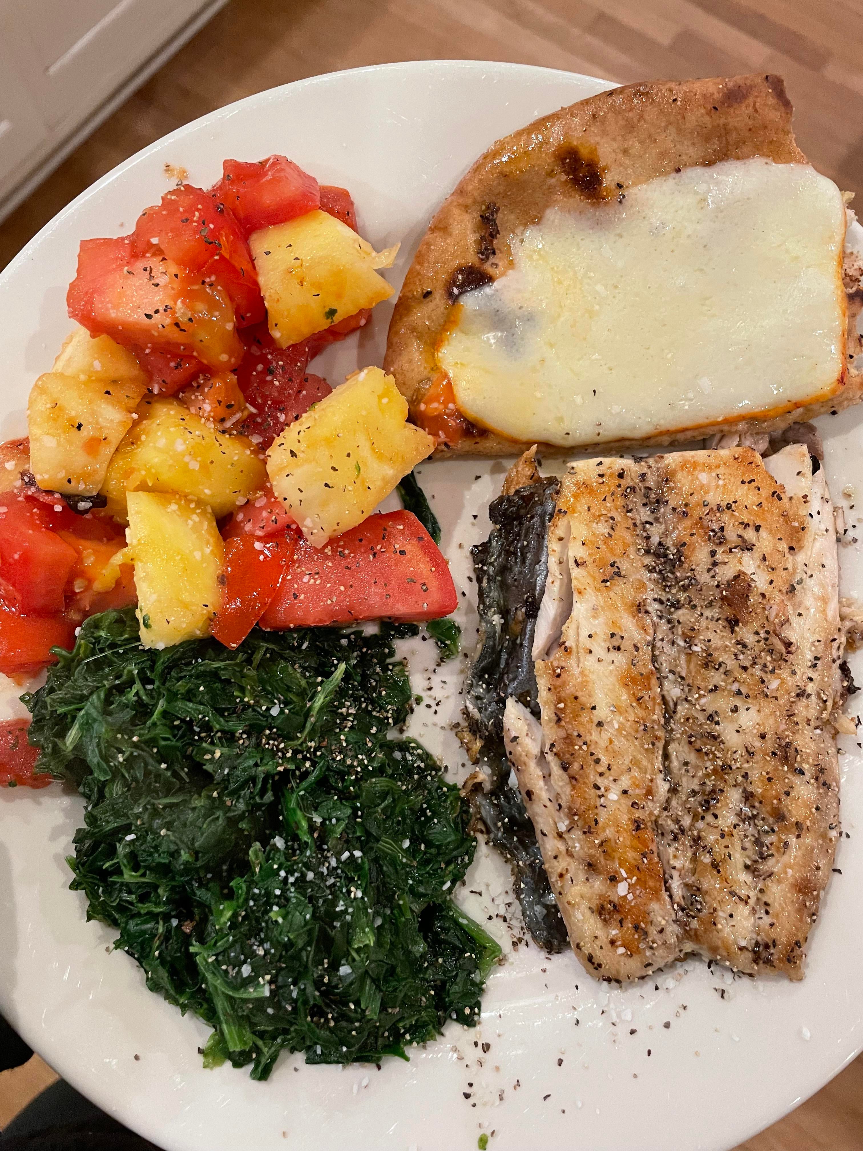 Pan fried sea bass with grilled pita and cheese, steamed spinach, and ...