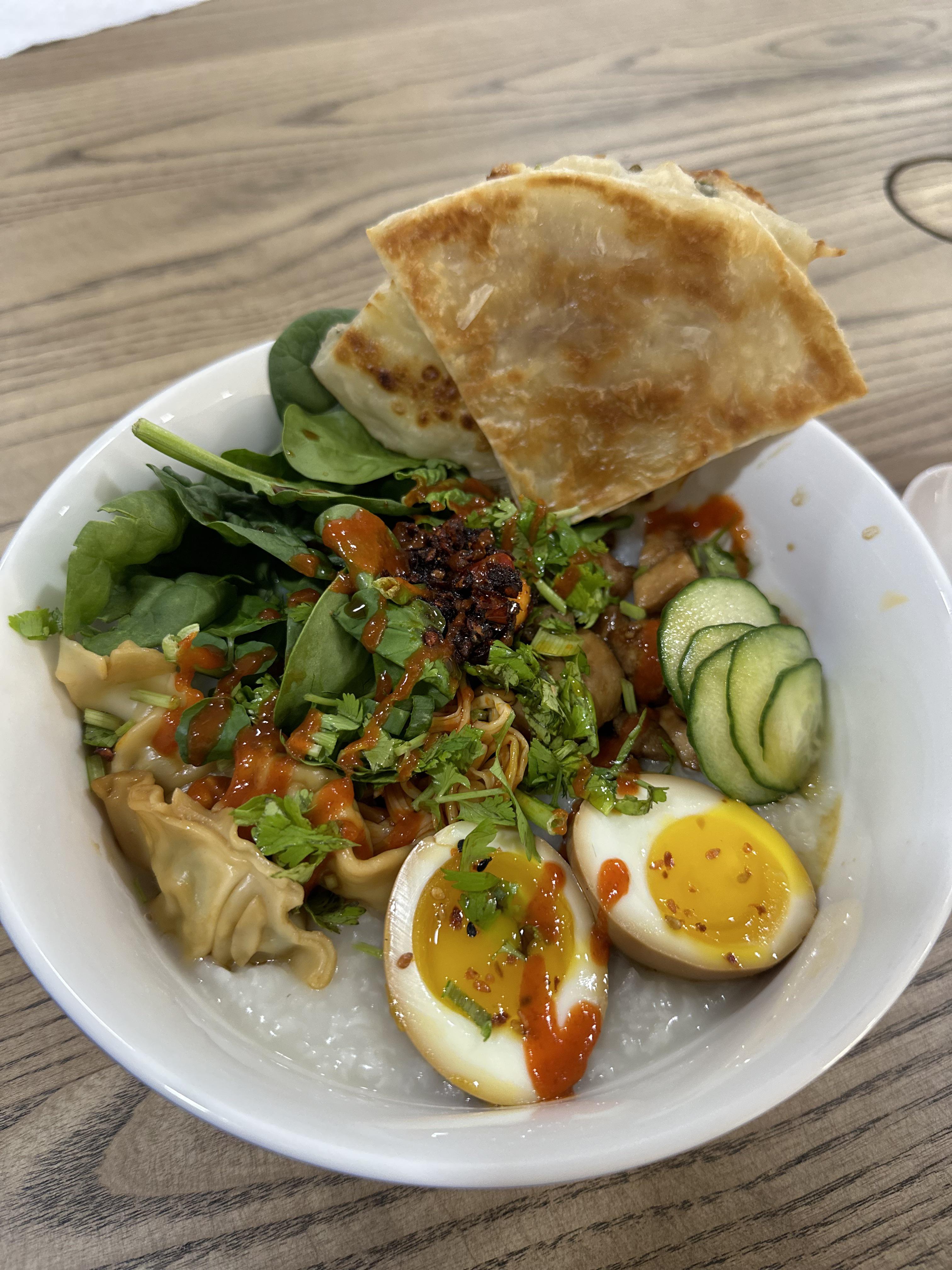 Congee with wontons, spinach, watercress, soy eggs, paratha, cilantro ...