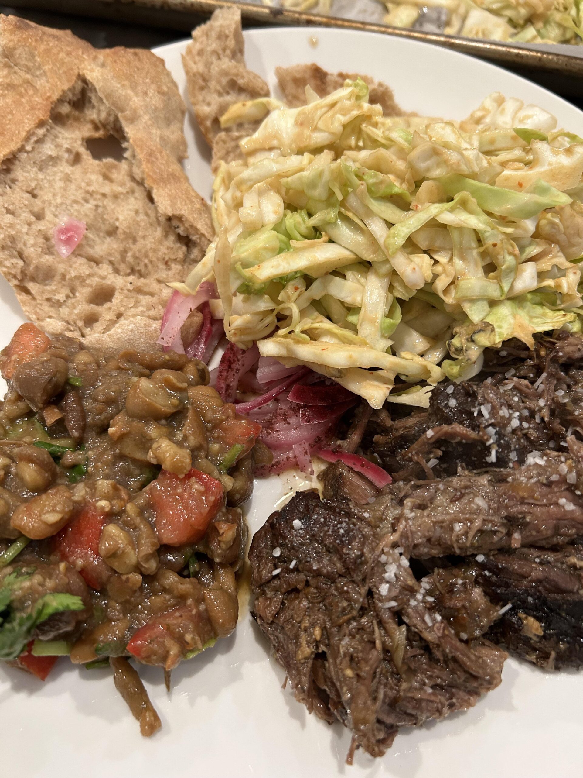Braised beef, ful, tahini dressed cabbage, some homemade flatbread ...